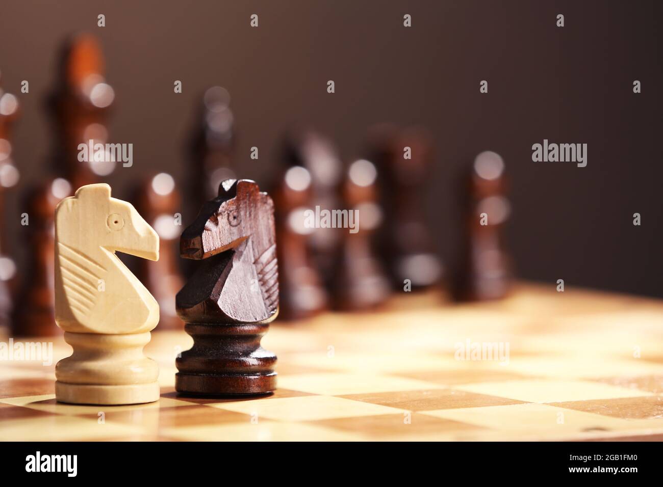 Chess pieces and game board on brown blurred background Stock Photo - Alamy