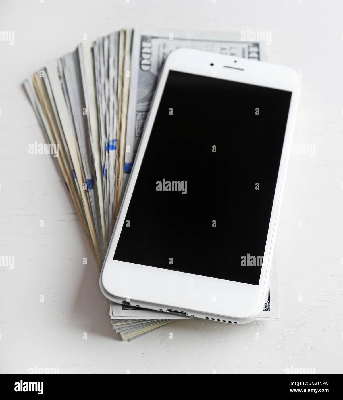 Smart phone on a stack of dollar banknotes over light table. Internet ...