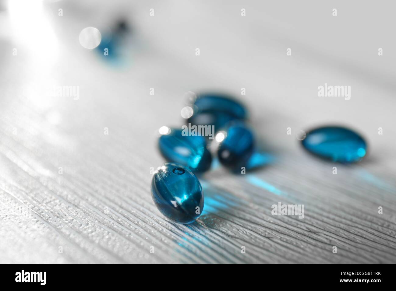 Transparent blue pills on a grey table, close up Stock Photo - Alamy