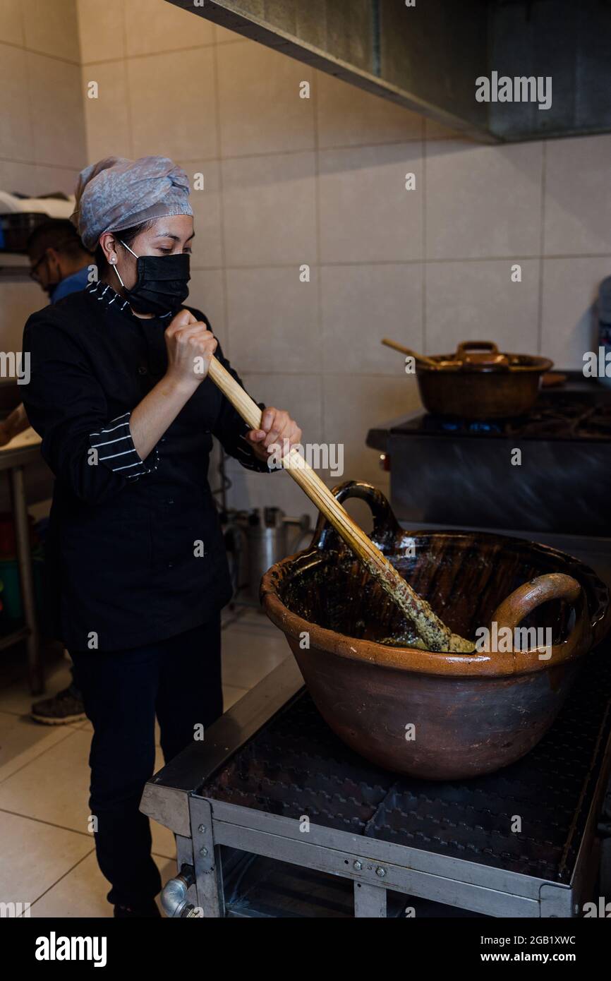 mexican woman cooking mole poblano food in a traditional clay pot in a ...