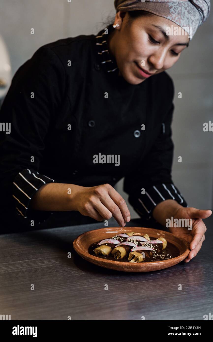 mexican woman cooking mole poblano enchiladas traditional food in a ...