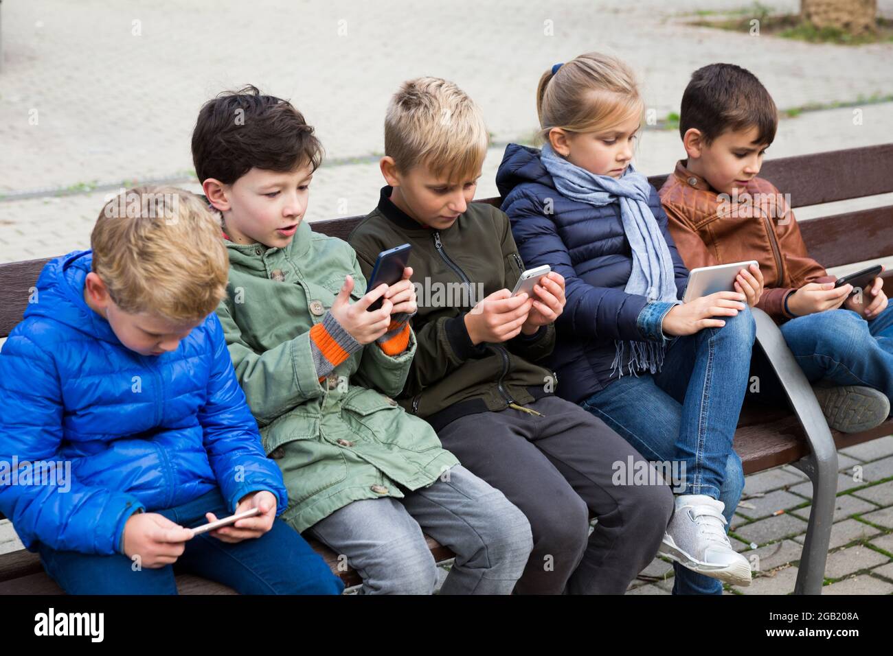 Kids playing with smartphones on bench Stock Photo - Alamy