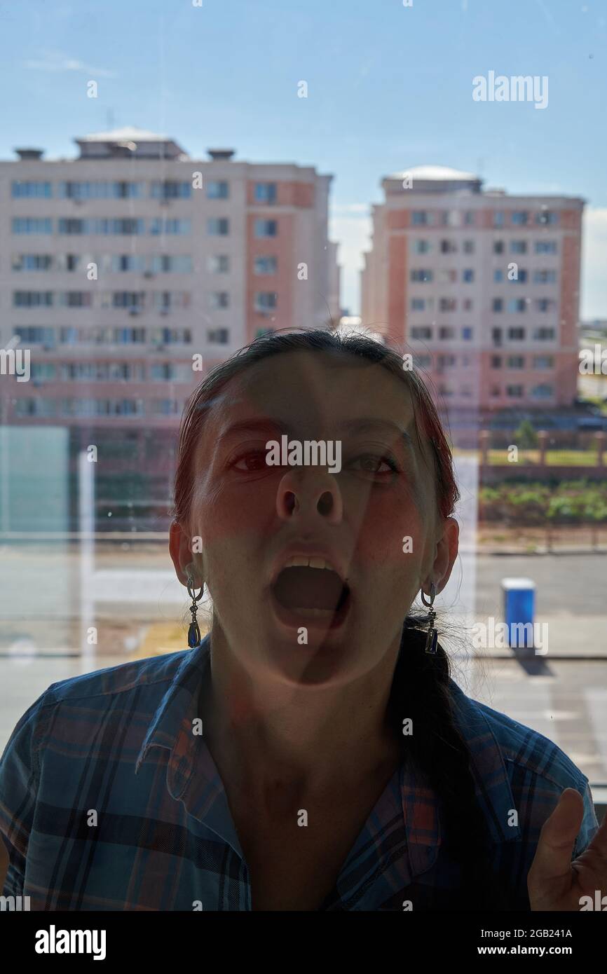 the girl is making faces outside the window Stock Photo - Alamy