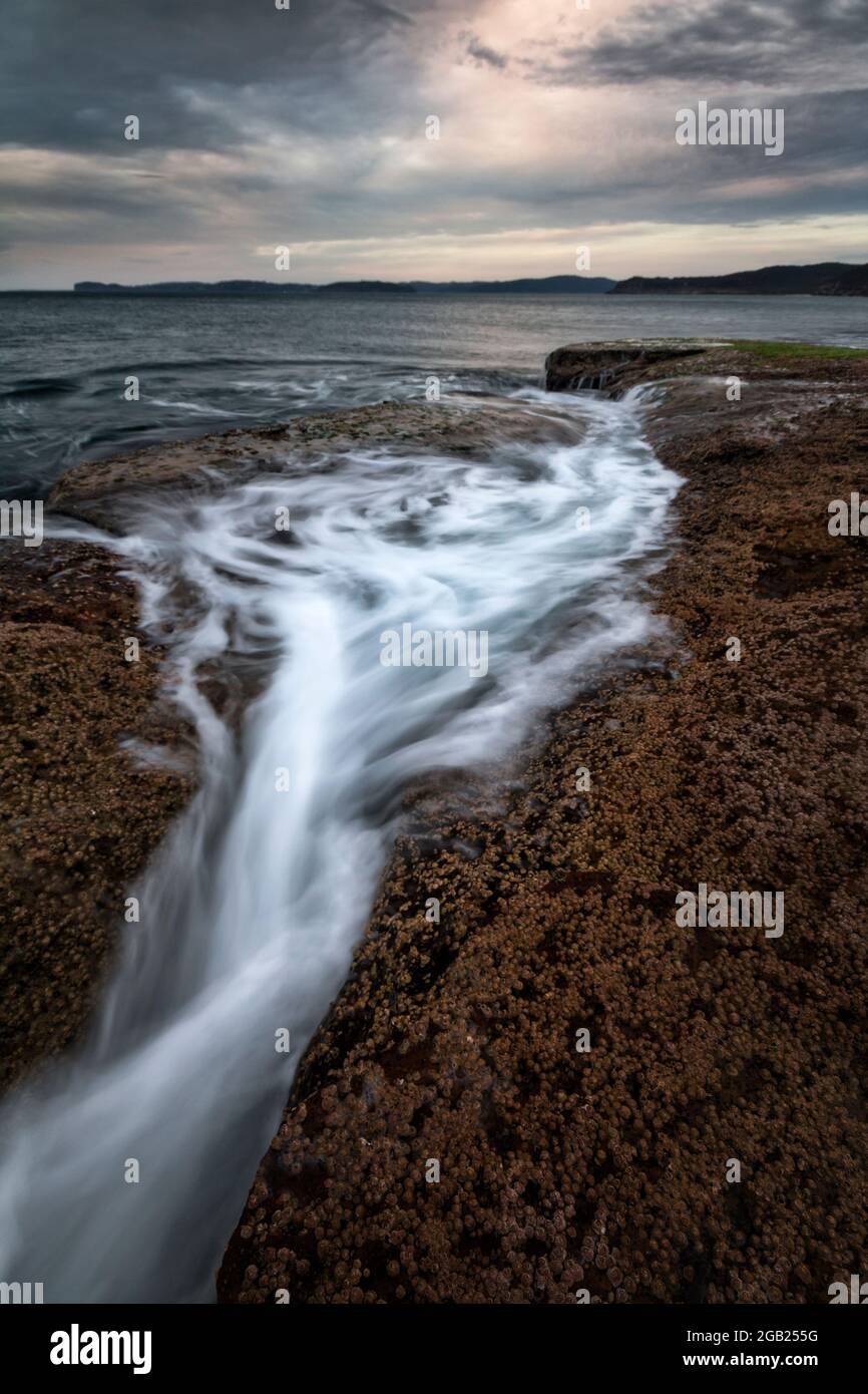 water flowing from the rocks out into the ocean along the coast Stock ...