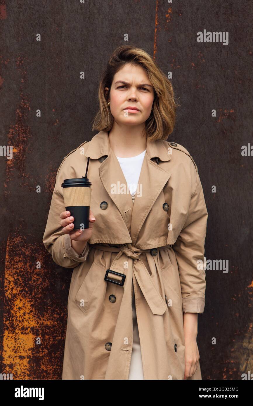 Young smiling millennial woman with wild hair dressed in an autumn coat ...