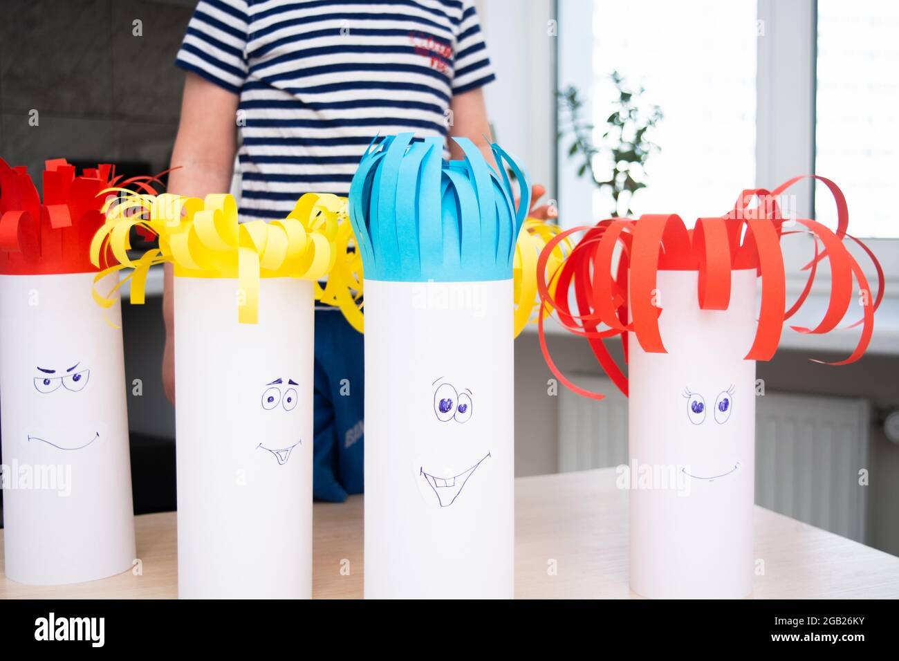Preschool boy cutting paper hair with scissors on handmade funny heads ...