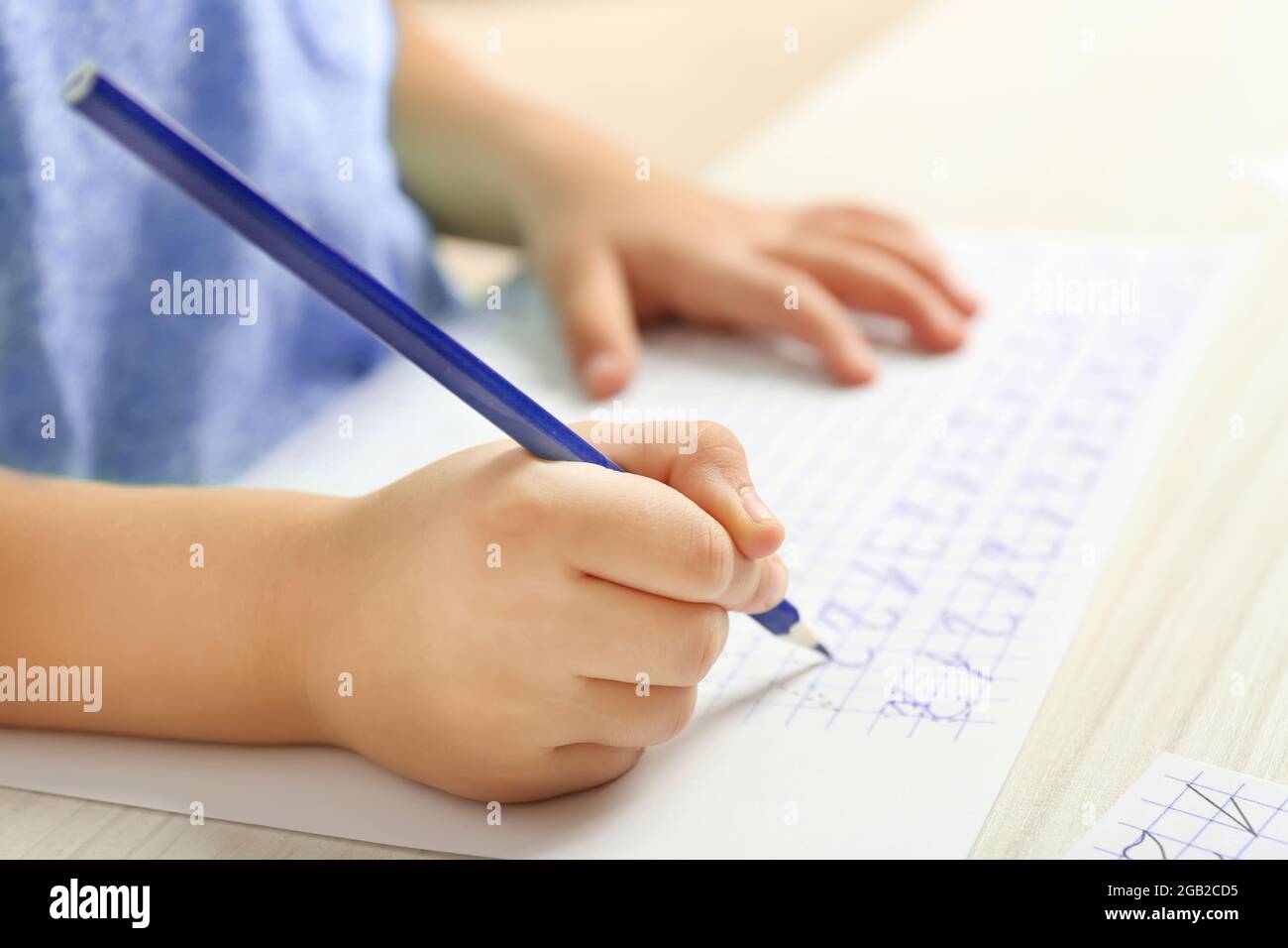 Schoolkid learns to write on sheet of paper, closeup Stock Photo - Alamy