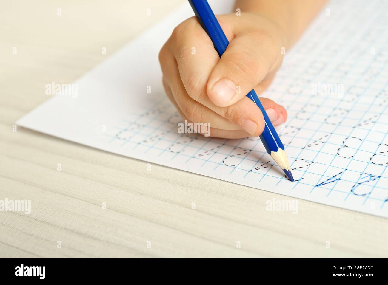 Schoolkid learns to write on sheet of paper, closeup Stock Photo - Alamy