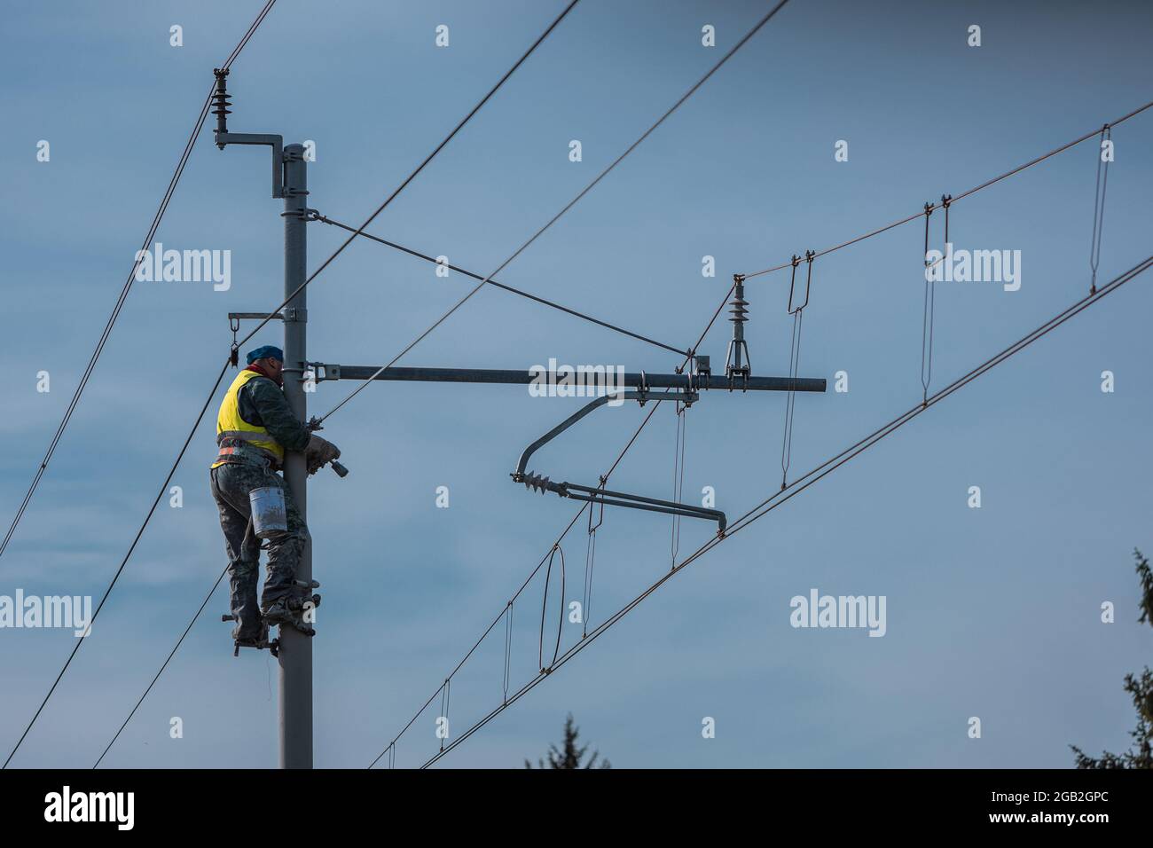 Painters or maintenance workers repairing catenary or electric poles ...
