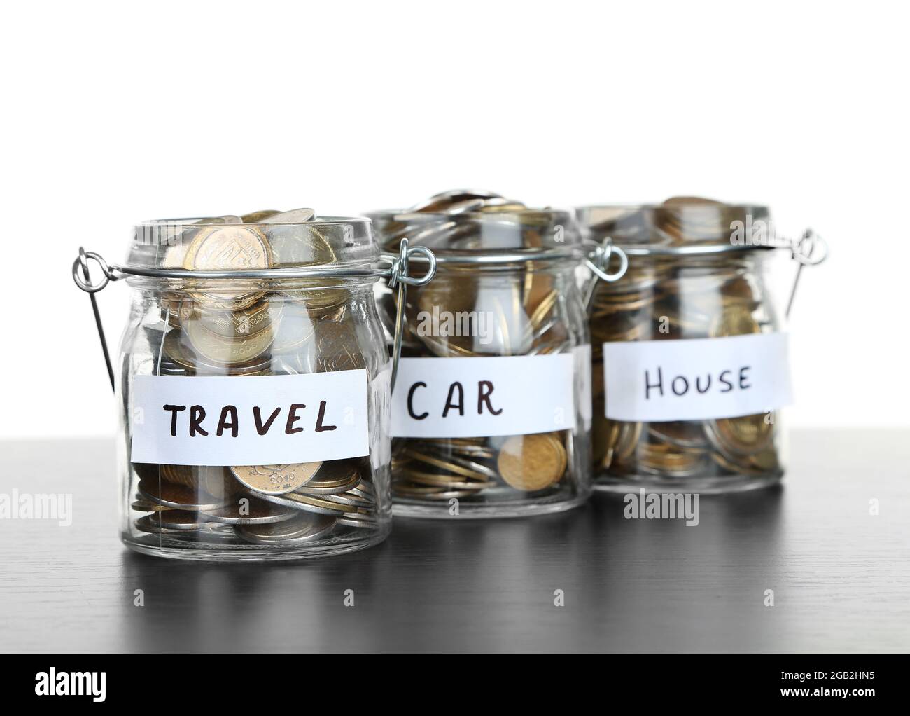 Three jars for different needs full of coins Stock Photo - Alamy