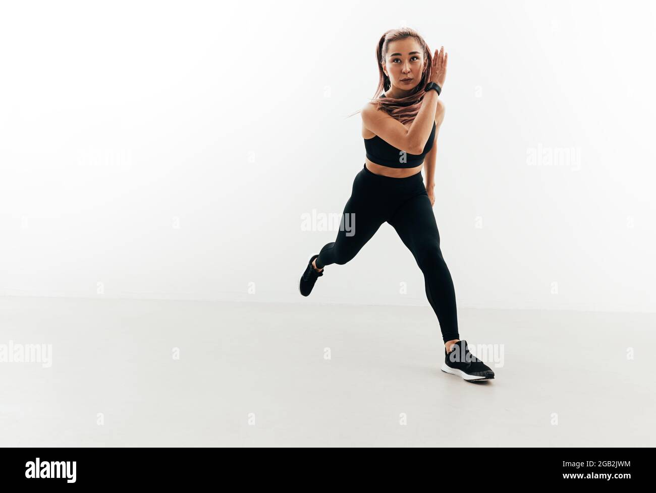 Muscular woman exercising in studio. Young female running forward Stock ...