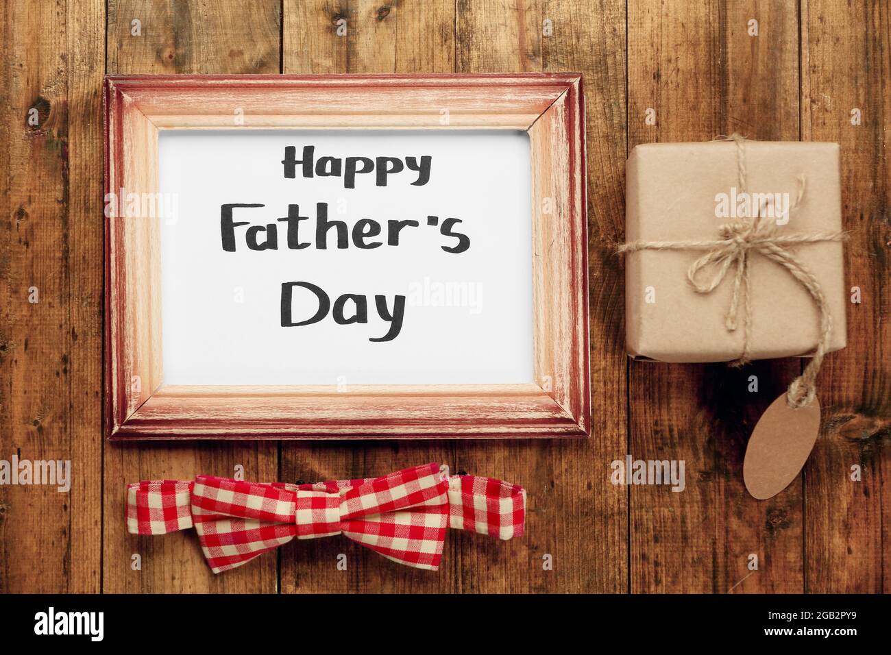A frame with Happy father's Day greeting, a wrapped box and a plaid bow ...