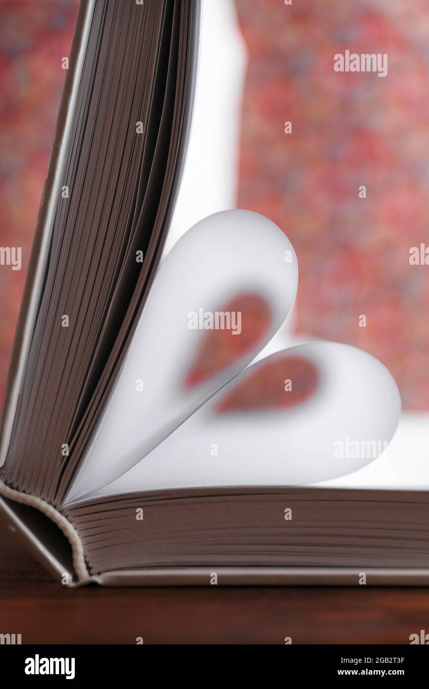 Heart from book pages on blurred background Stock Photo - Alamy
