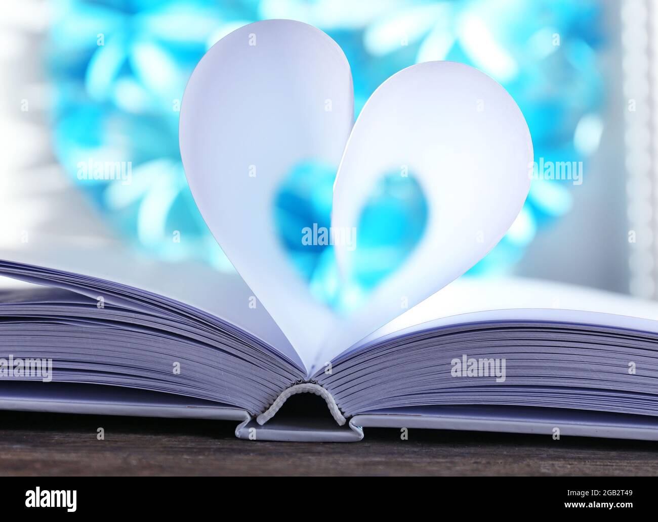 Heart from book pages on blurred background Stock Photo - Alamy