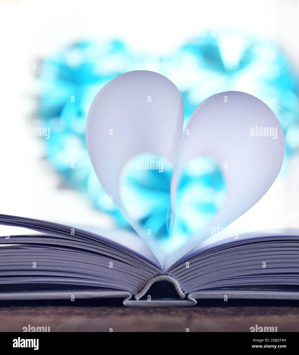 Heart from book pages on blurred background Stock Photo - Alamy