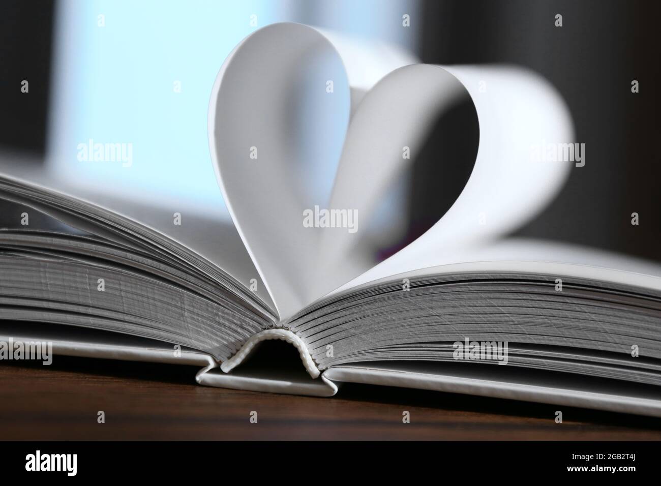Heart from book pages on dark blurred background Stock Photo - Alamy