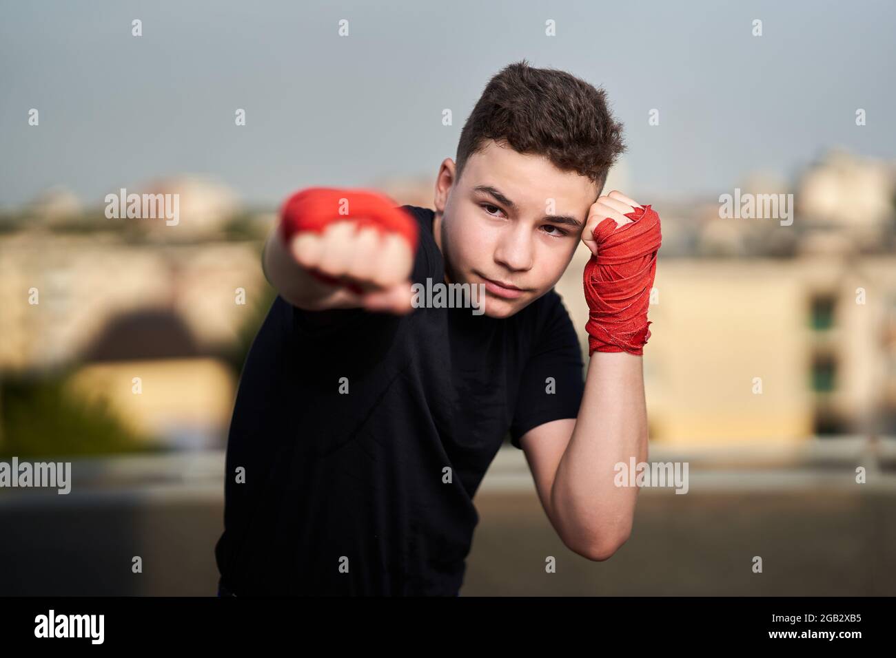 Young teenage kickboxer fighter training on the roof with buildings in ...