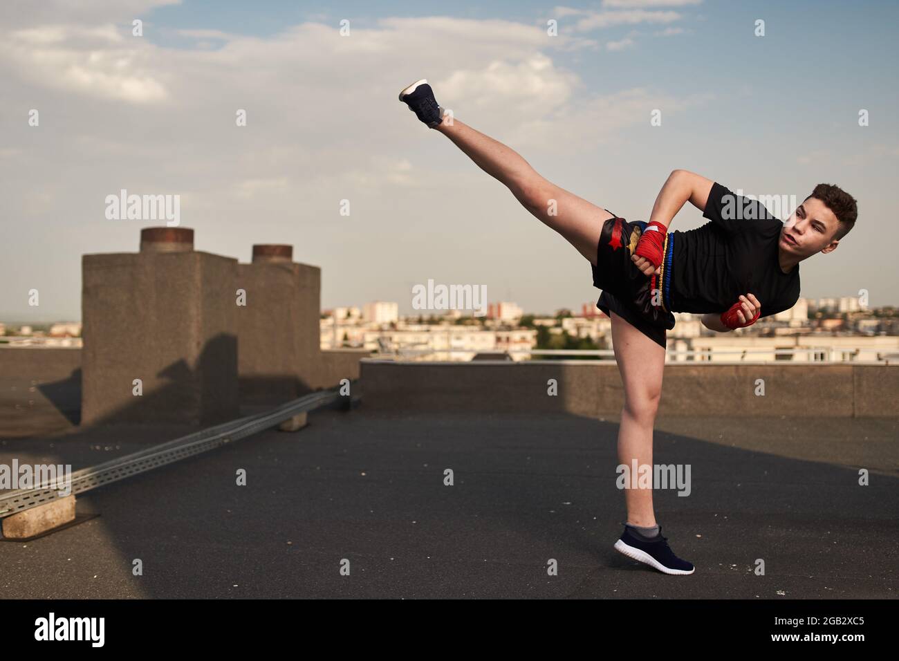 Young teenage kickboxer fighter training on the roof with buildings in ...