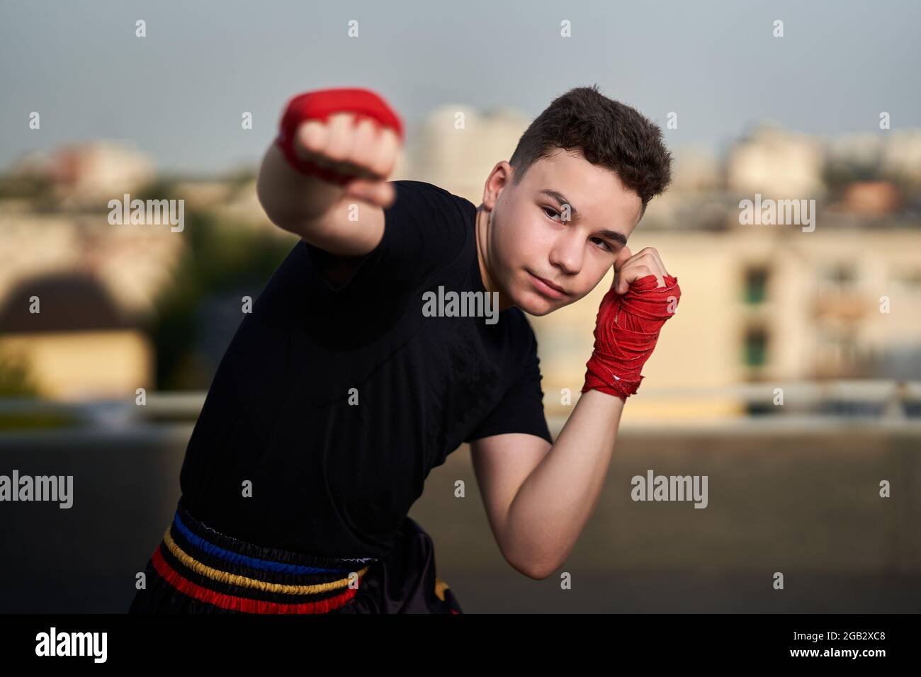 Young teenage kickboxer fighter training on the roof with buildings in ...