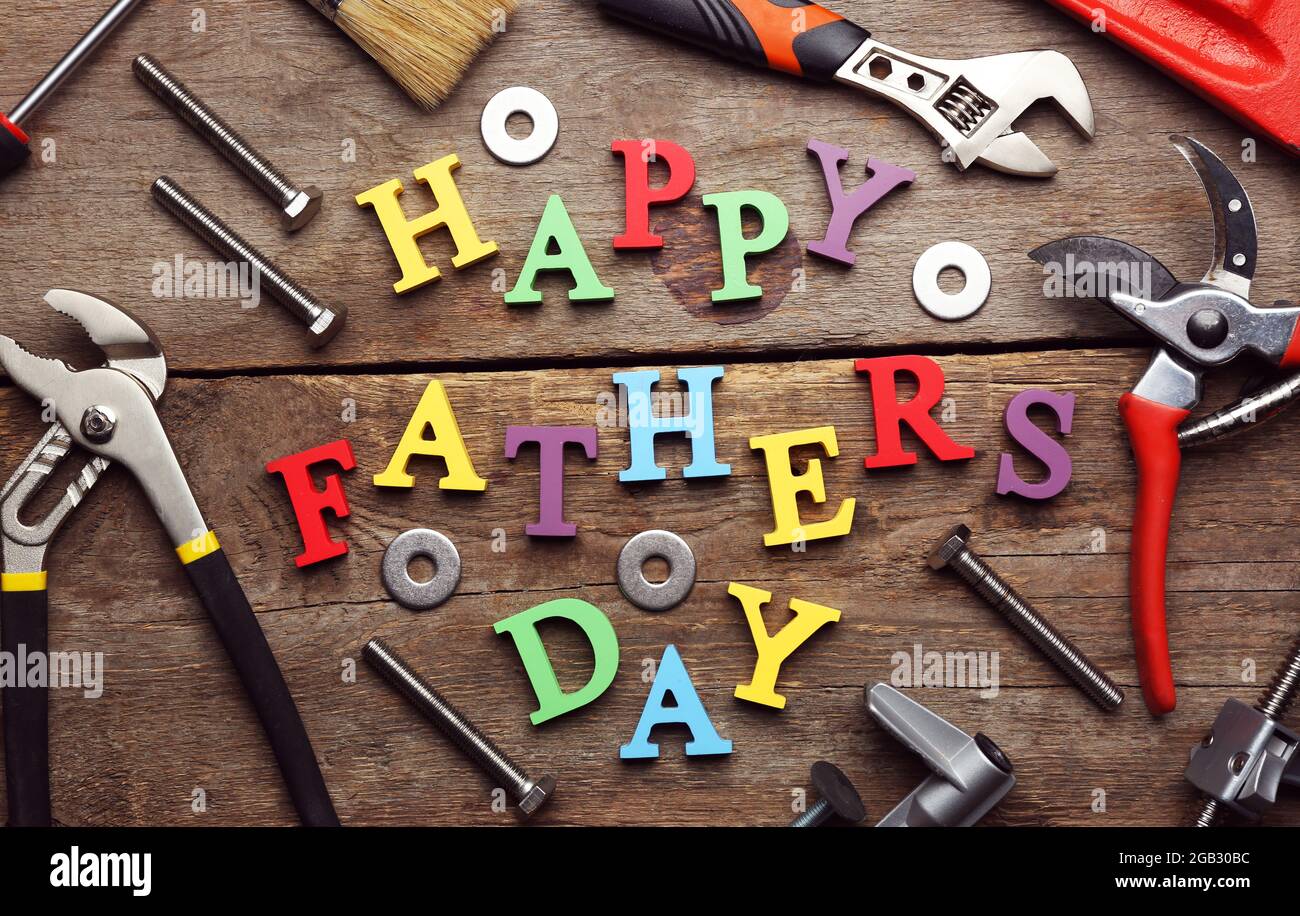 Happy Father's Day inscription with work tools on wooden background ...