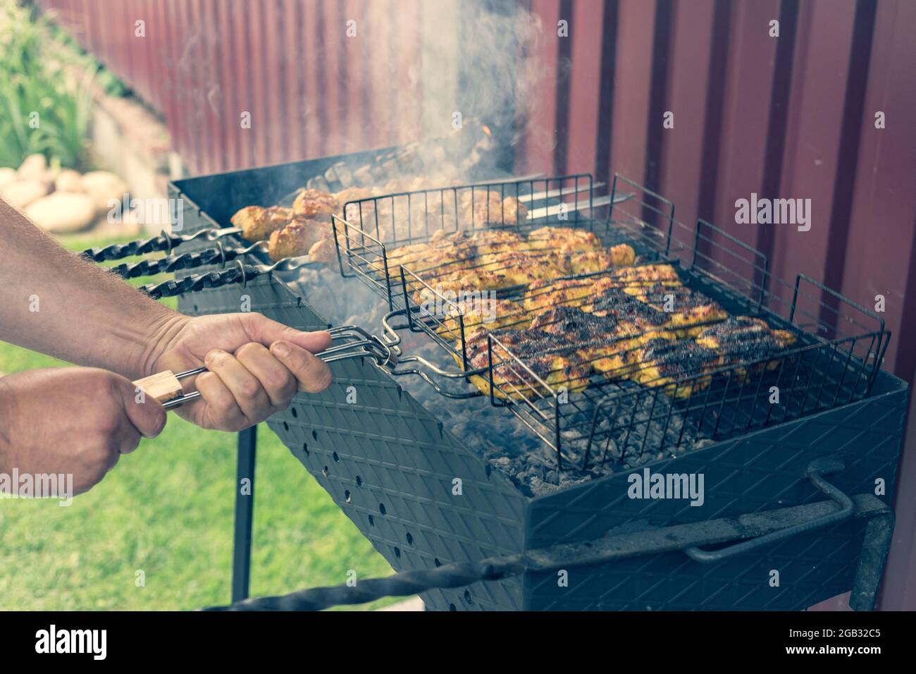 Hand rotates a skewer with a kebab on the grill Stock Photo - Alamy