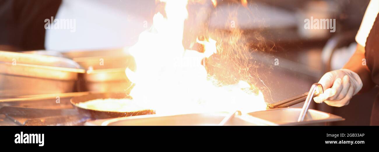 Chef cooking flambe on food in restaurant kitchen closeup Stock Photo ...