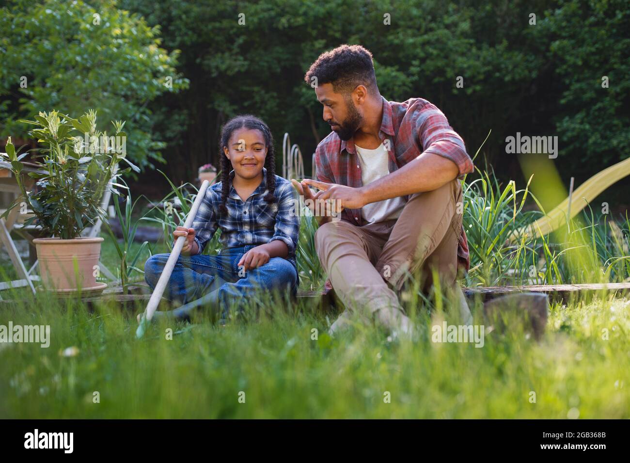 Happy young father with small daughter working outdoors in backyard ...