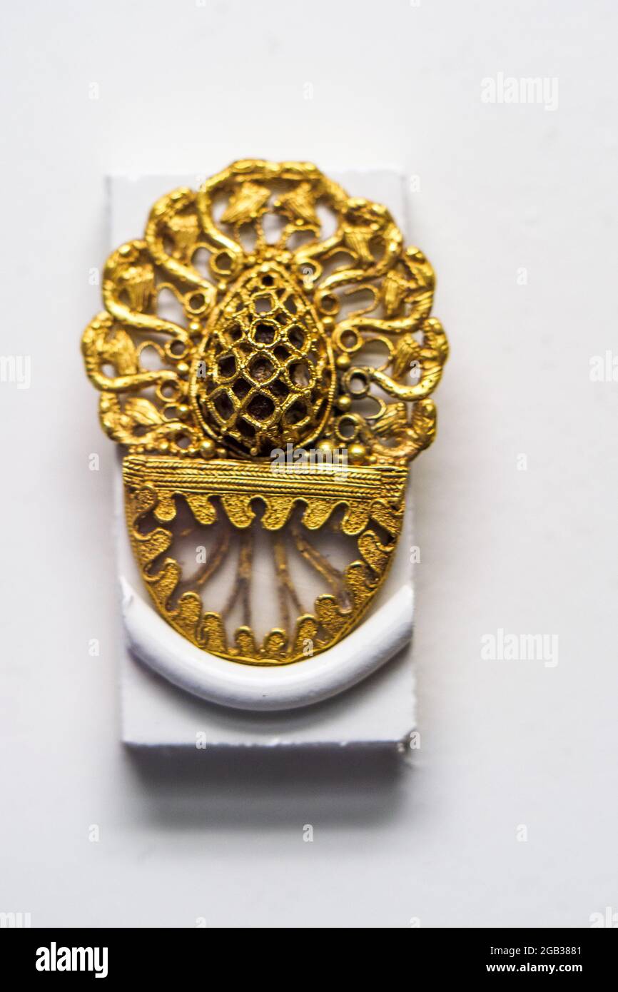 Semicircular gold stud decorated with bearded snakes; at the base a ...