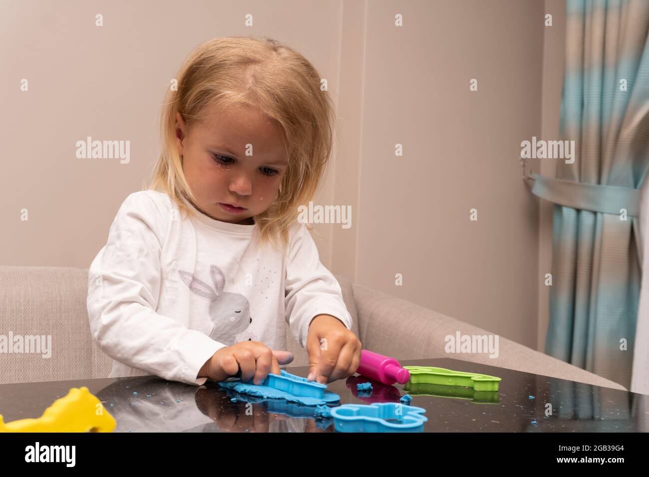Crying kid plays with colorful playdough Stock Photo - Alamy