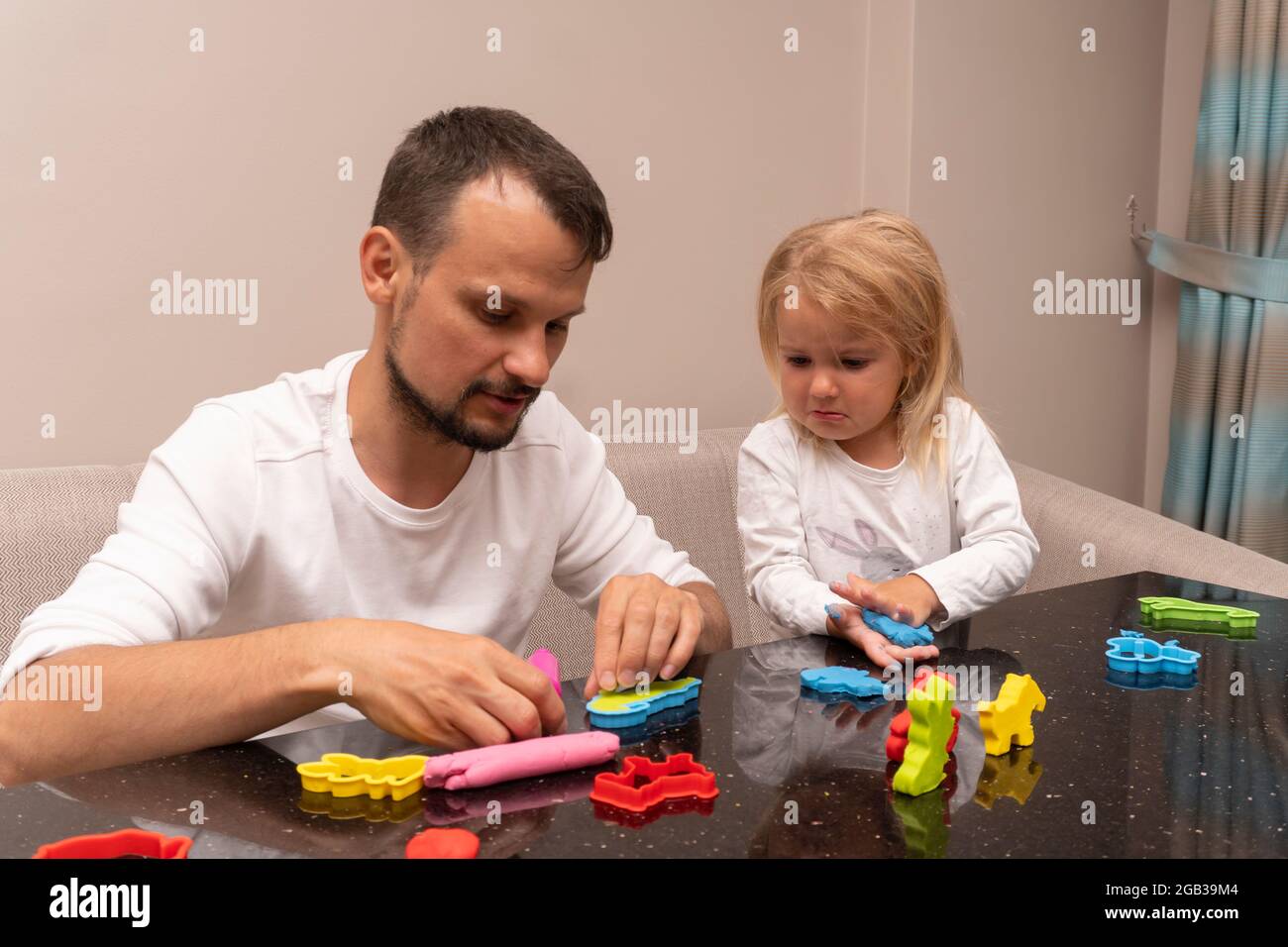 Crying little child and young caucasian dad play with colorful play ...