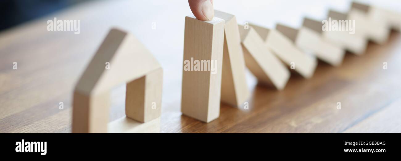 Male hand stoping falling wooden blocks on toy house closeup Stock ...