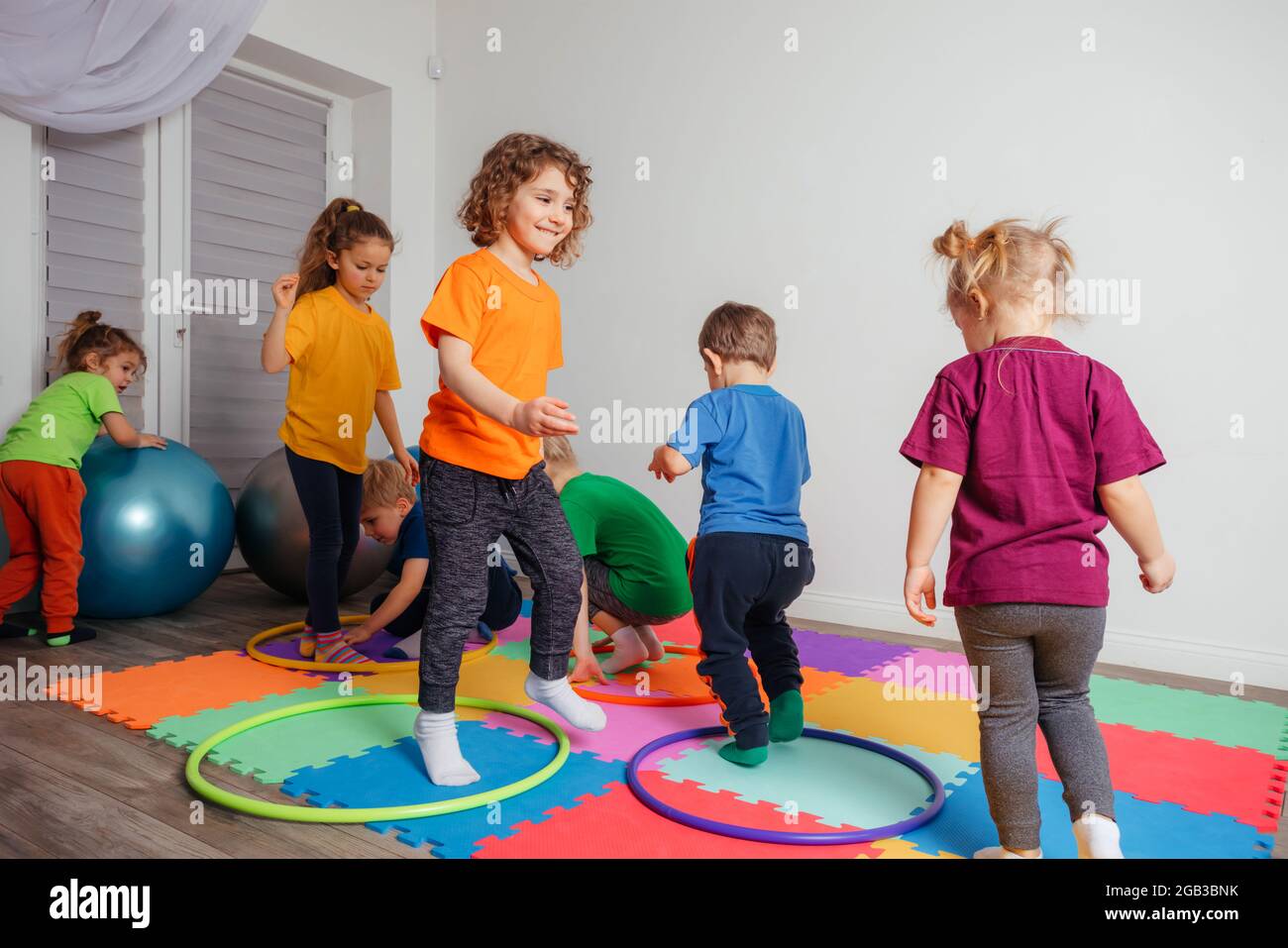 Children running and jumping around multicolor hoops on a floor Stock ...