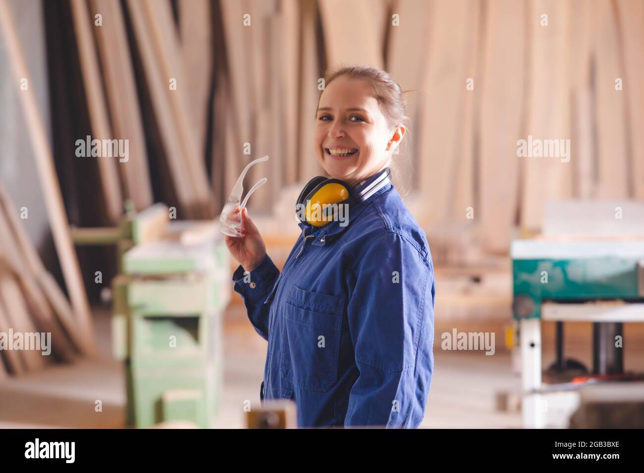 Cheerful female production operator in blue coverall Stock Photo - Alamy