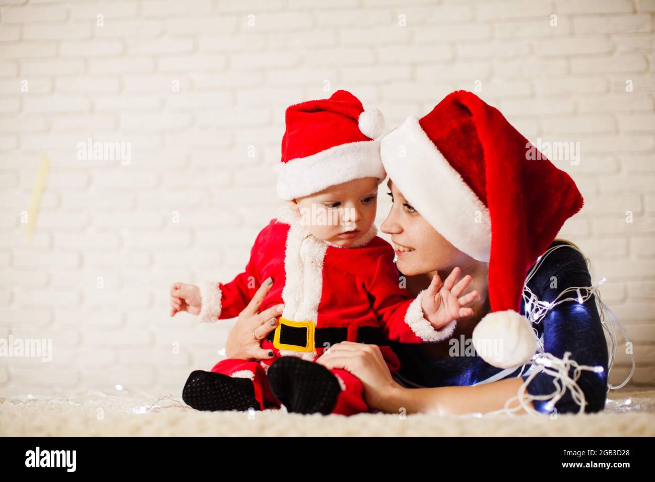 Mom with baby in santa claus costume tangled in garlands Stock Photo ...