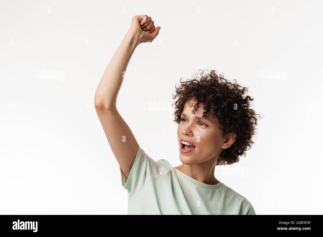 Young curly excited woman screaming while winner gesture isolated over ...
