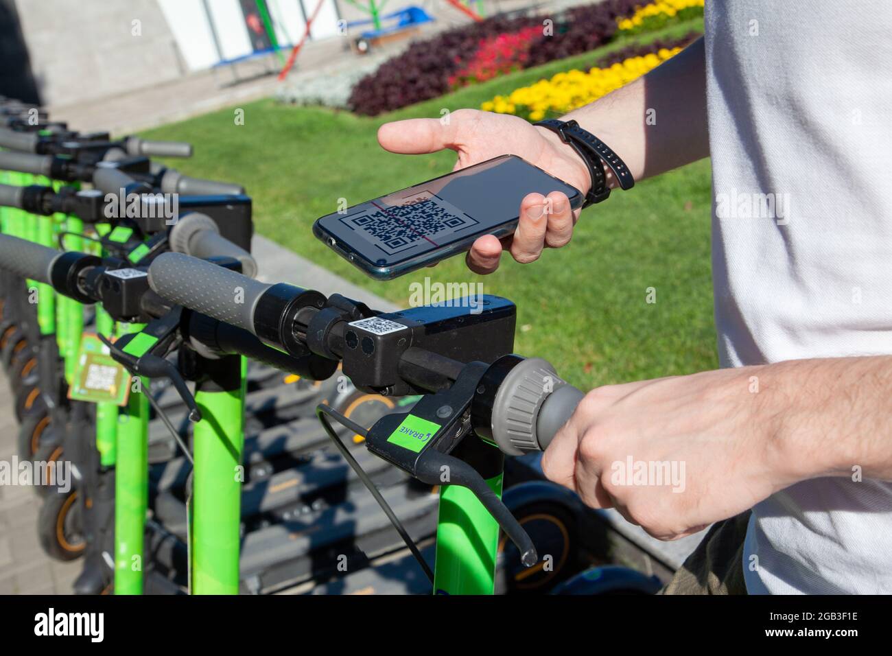 A young man rents an electric scooter by scanning the QR code with a ...