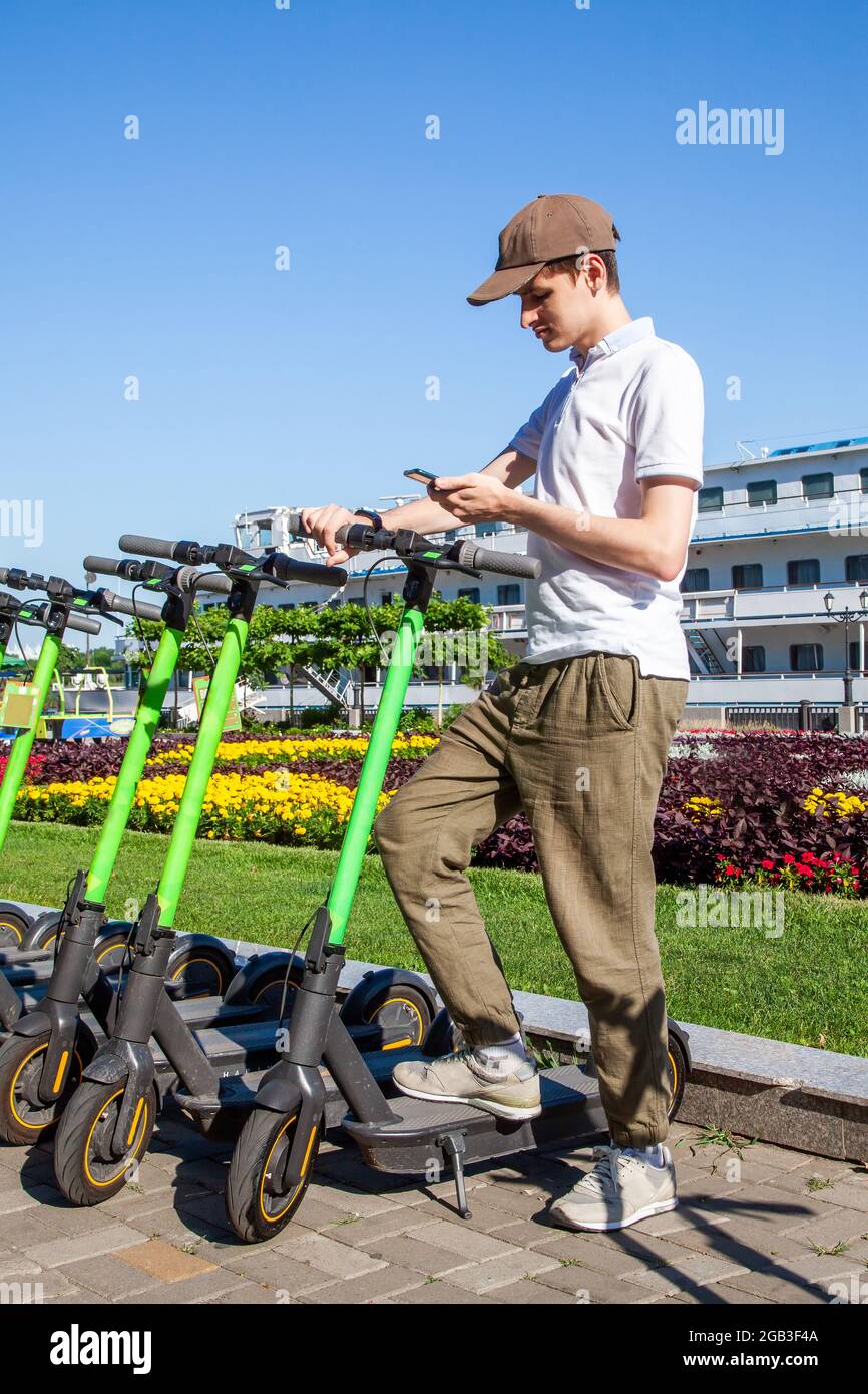 A young man rents an electric scooter by scanning the QR code with a ...