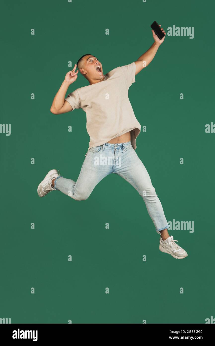 Portrait of young handsome asian man jumping with smartphone isolated ...