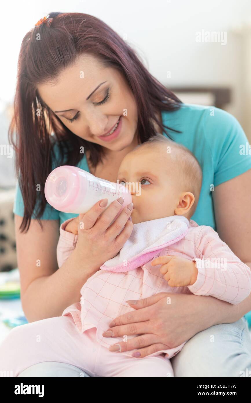 Mother feeding baby girl with bottle at home Stock Photo - Alamy