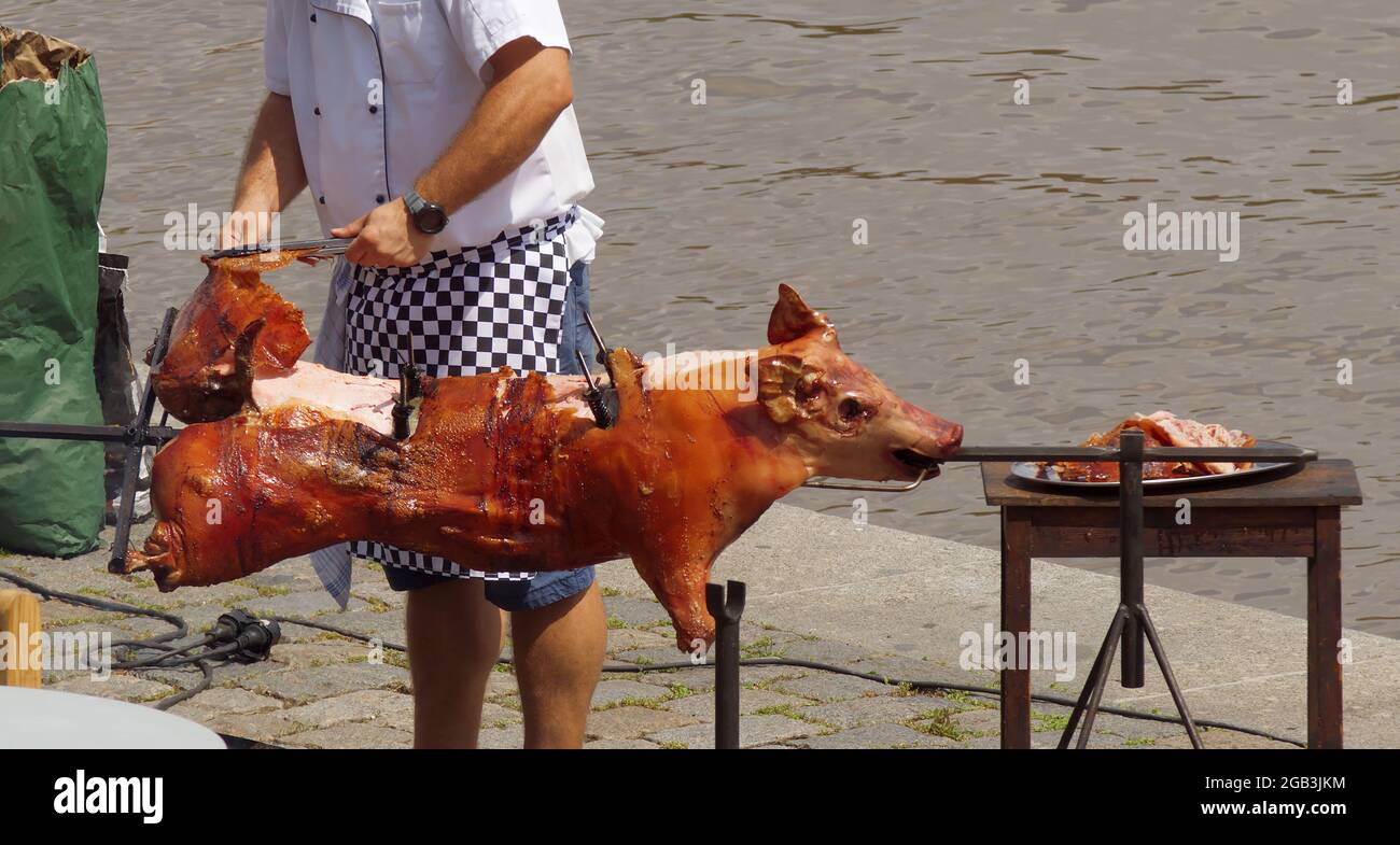 Slicing grilled piglet. The chef cuts a freshly grilled pig with a ...