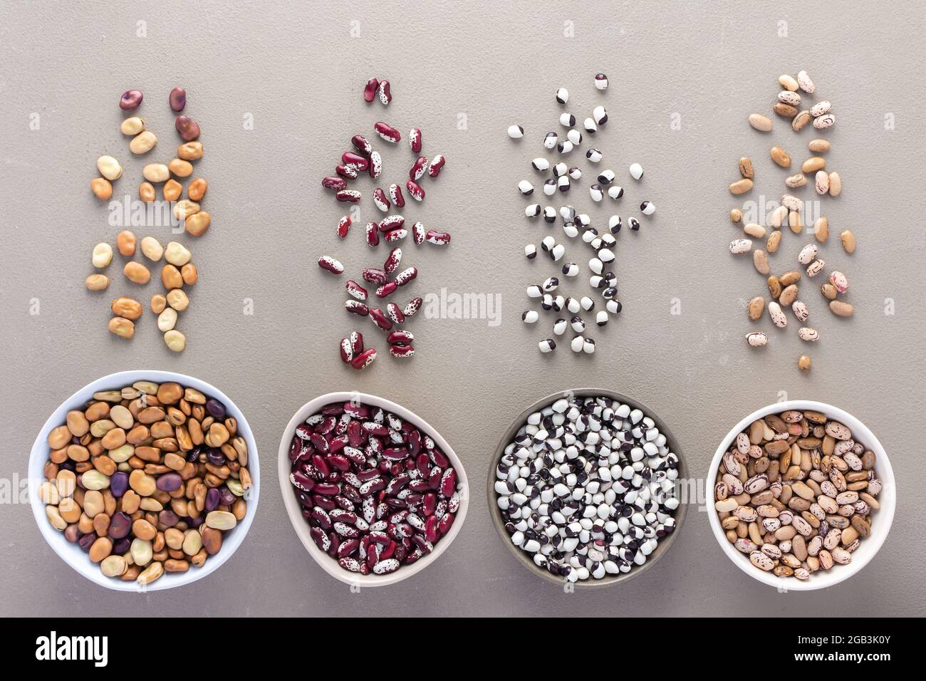 Different types of legumes in bowls and scattered in the background ...