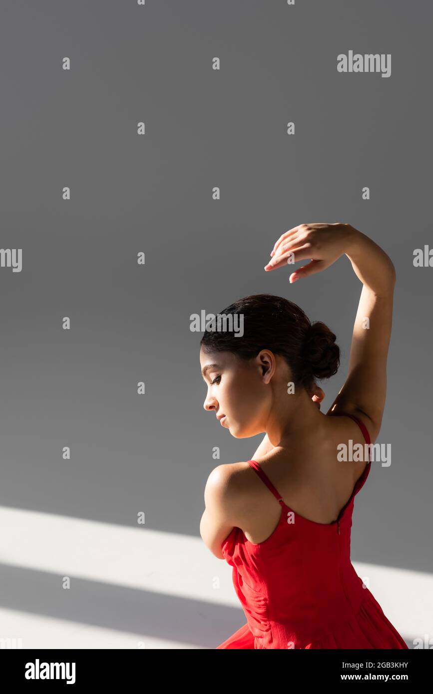 Side view of classical dancer in red dress on grey background with ...