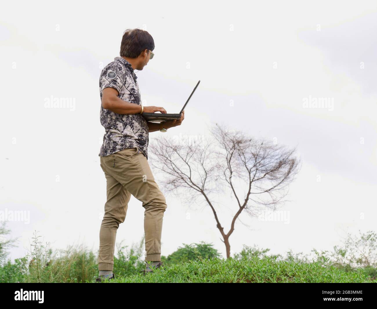 stylish boy holding laptop computer around natural sky background with ...