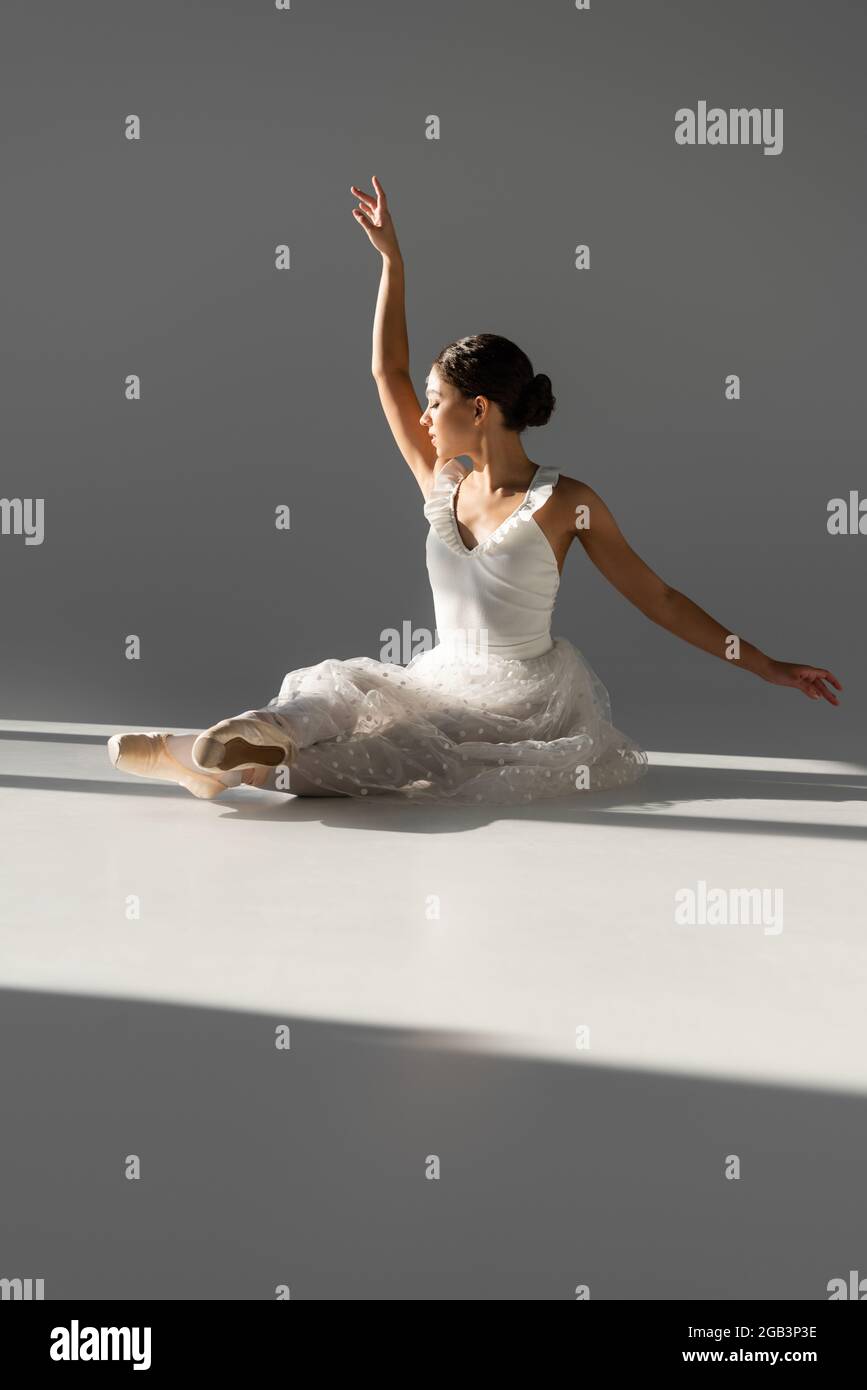 Side view of elegant ballerina sitting on grey background Stock Photo ...