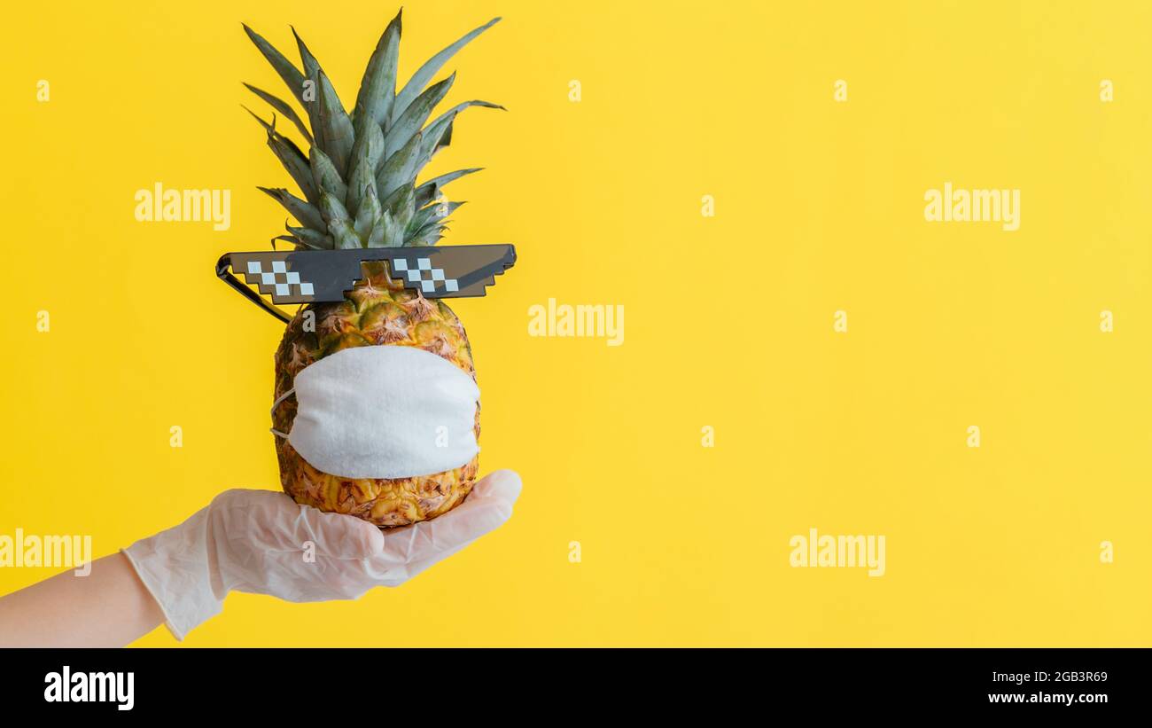 Funny pineapple face in a protective medical mask. Doctor hand in ...