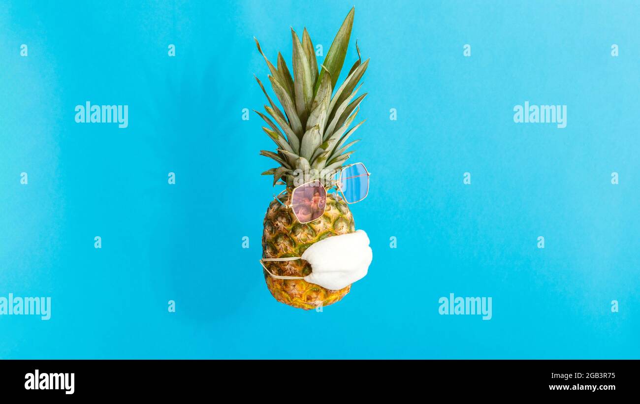 Pineapple in pink sunglasses medical mask on color blue summer ...