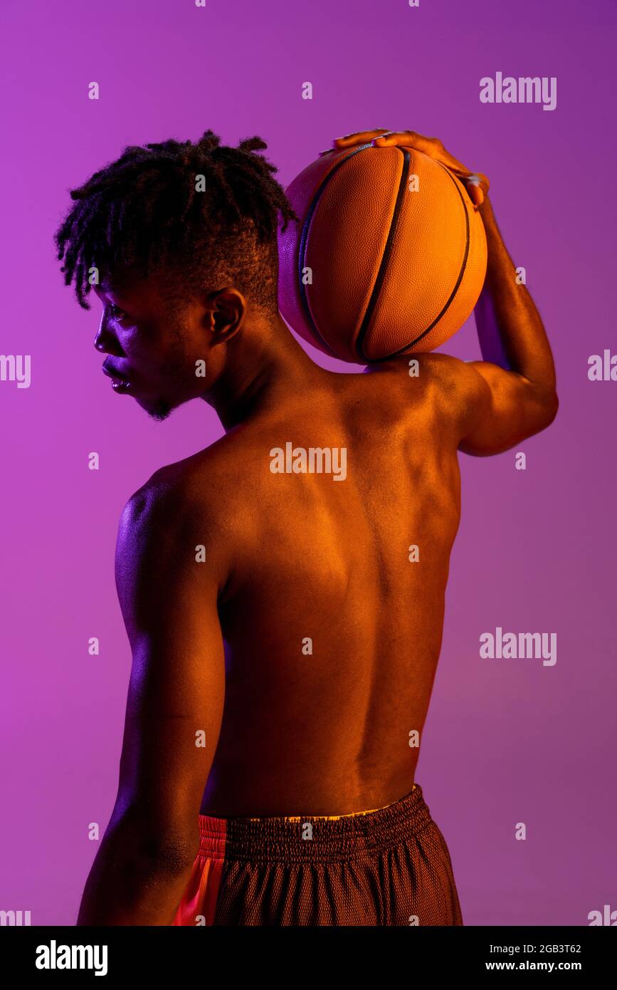 Back view. Young african man, basketball player posing with ball ...