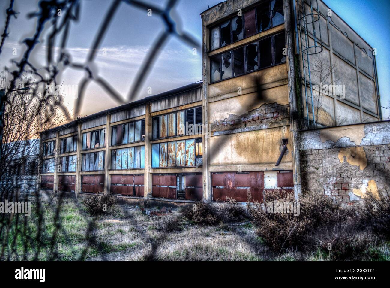 Exterior of an abandoned factory through a metal wire fence Stock Photo ...
