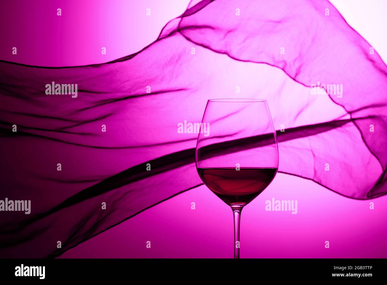 Glass of red wine on a background of a waving satin curtain. Purple ...