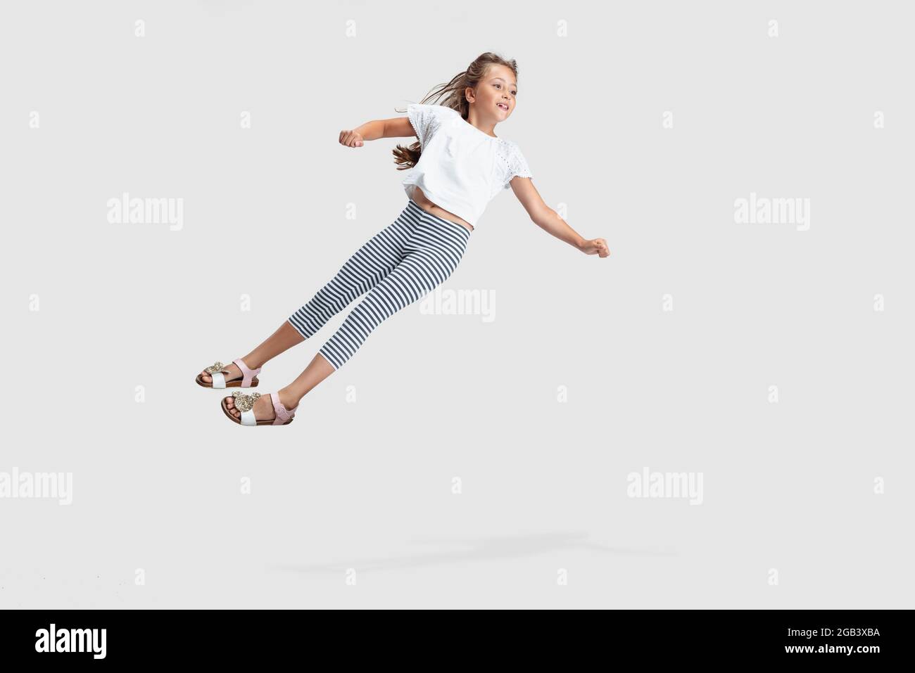 Full-length portrait of beautiful little girl falling down isolated on ...